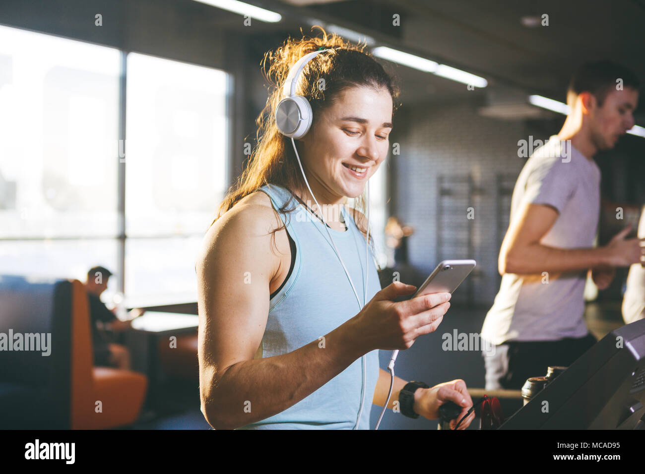 Theme sport and music. A beautiful Caucasian woman running in gym on ...