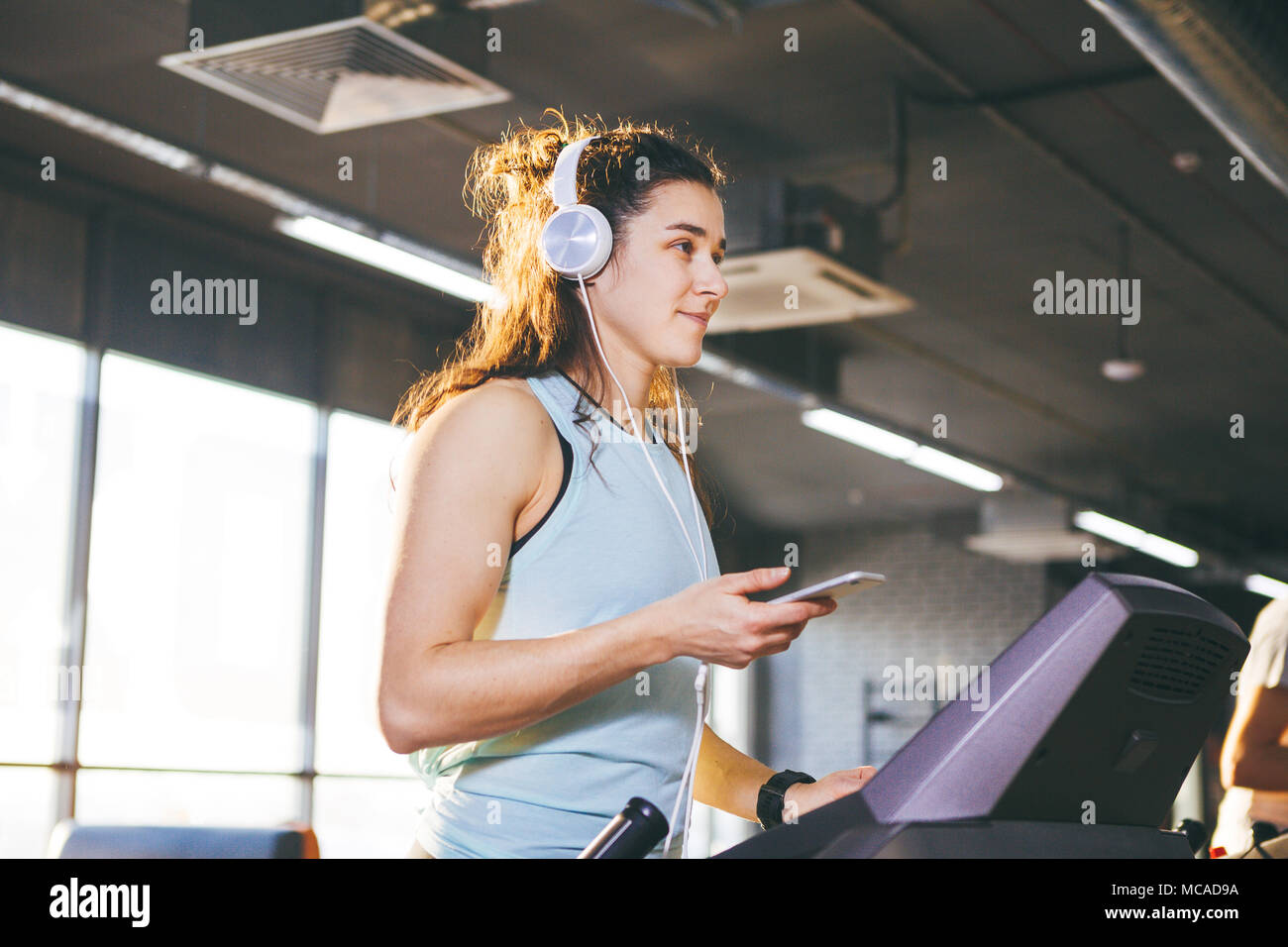 Theme sport and music. A beautiful Caucasian woman running in gym on ...