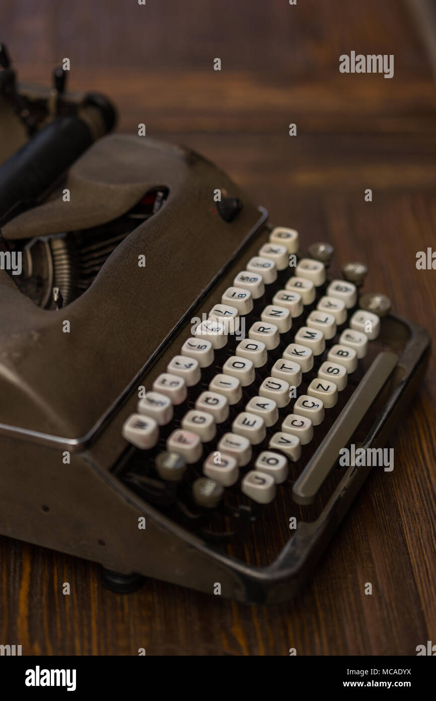 Vintage dark gray typewriter with white keys on a wooden tabletop ...