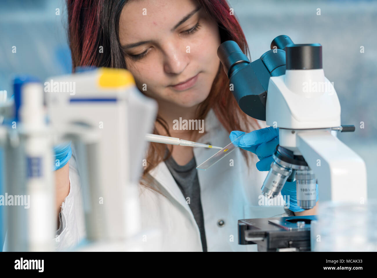 pretty female laboratory assistant analyzing a biological sample at ...