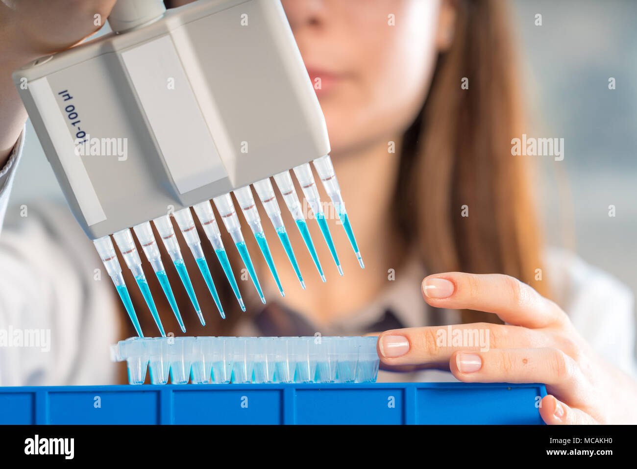 student woman with multi pipette and other PCR items in microbiological ...