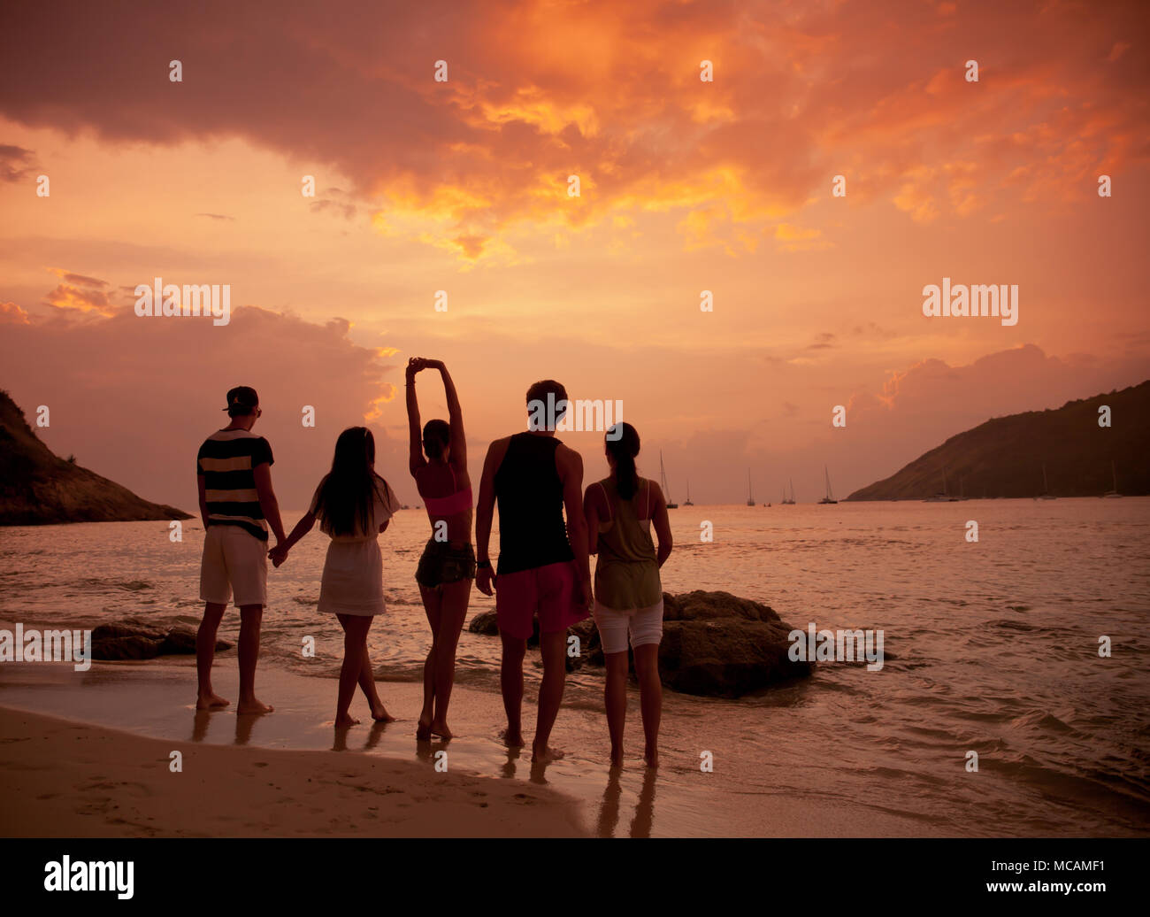 Group of happy people at sea beach at sunset Stock Photo - Alamy