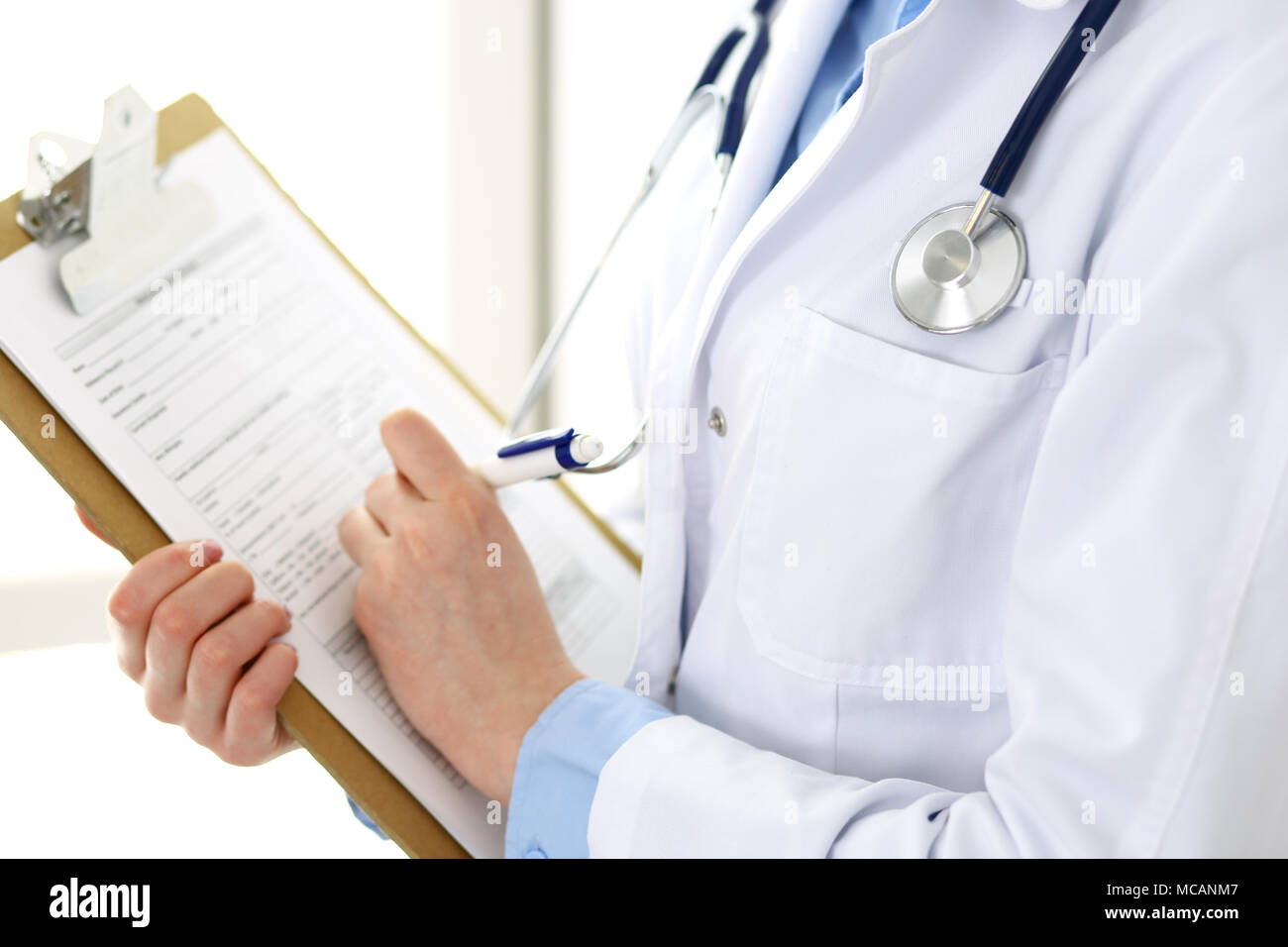 Female doctor filling up medical form on clipboard closeup. Physician ...