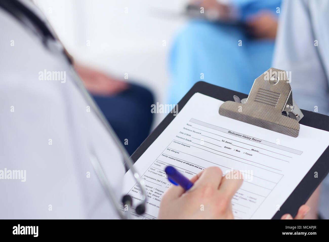 Close Up of a female doctor filling out application form while talking ...