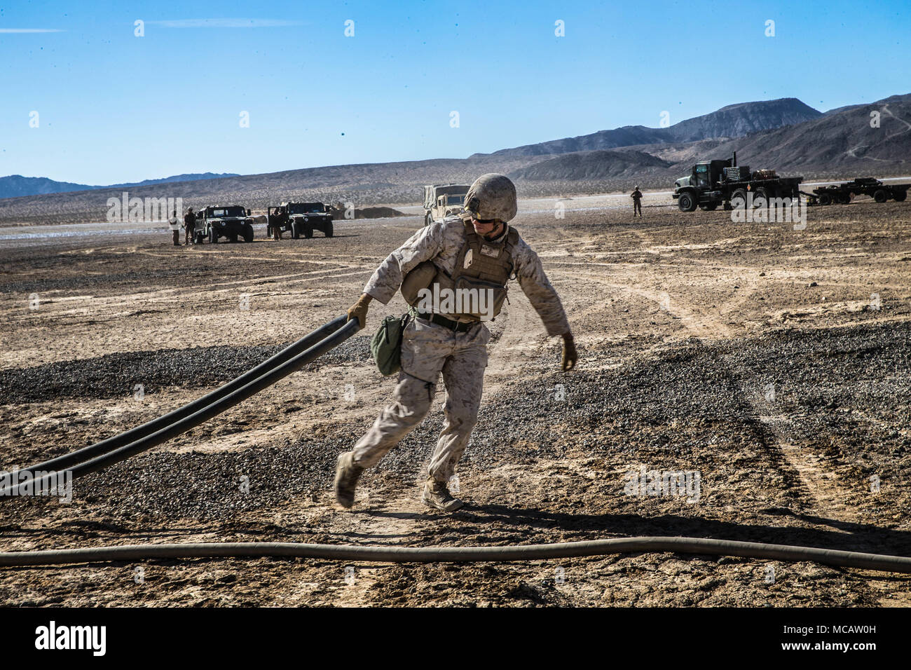 A Marine with Marine Wing Support Squadron 371 carries a jet fuel line ...