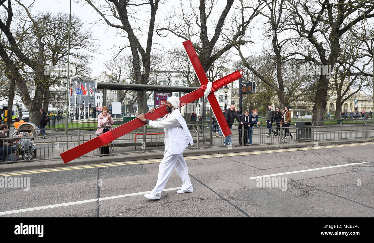 Brighton UK 15th April 2018 - A man carrying a large cross joins the ...