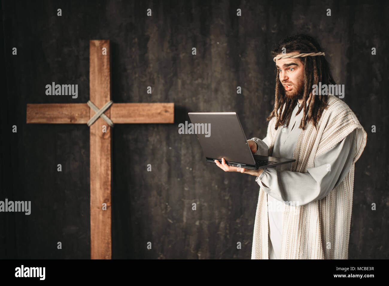 Man in the image of Jesus Christ uses laptop Stock Photo - Alamy