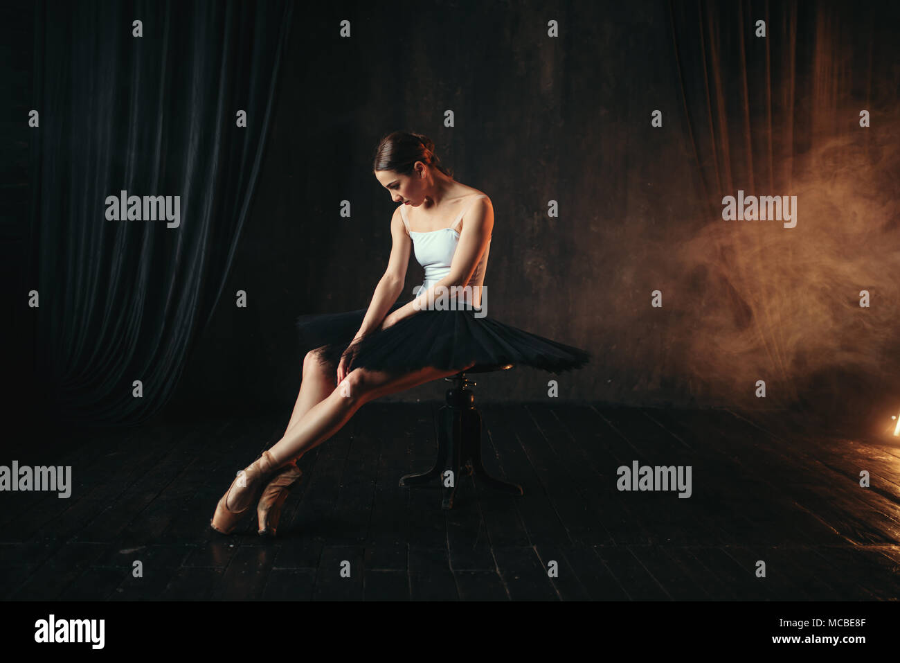 Ballet dancer sitting on black banquette Stock Photo - Alamy