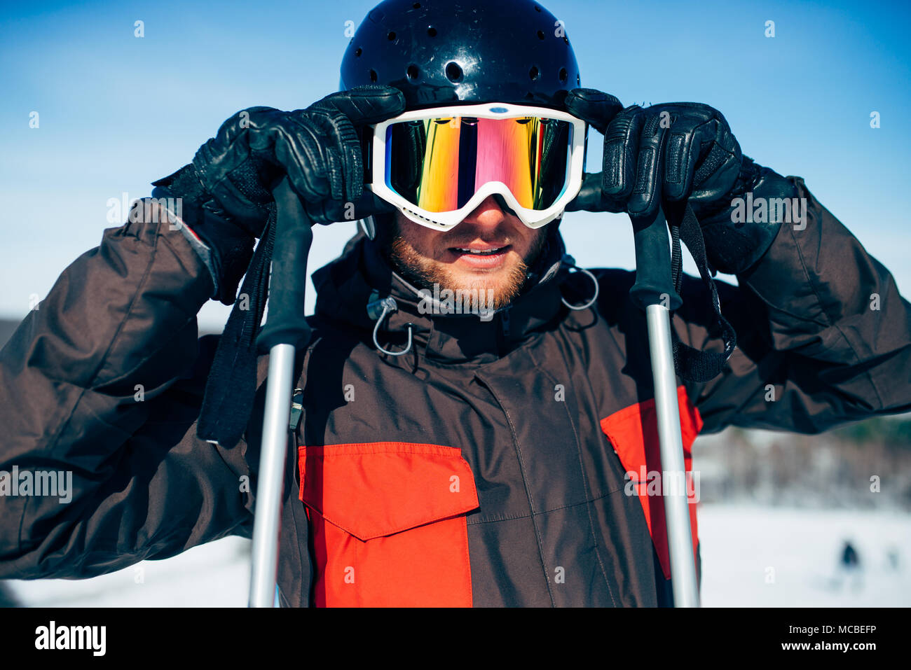 Male skier in helmet puts on glasses, front view Stock Photo - Alamy