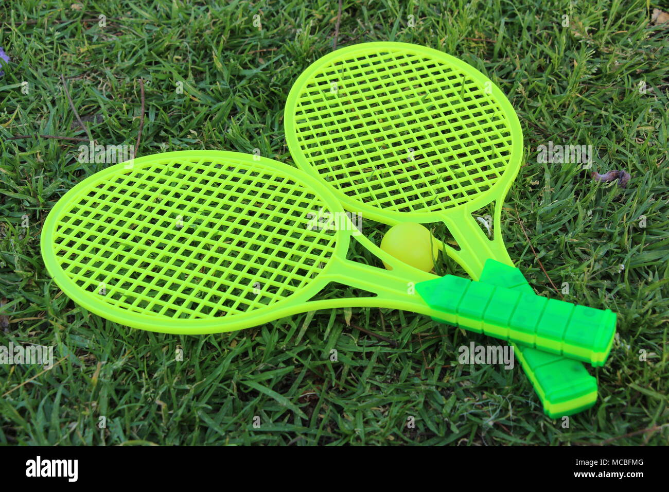 Tennis rackets toy with ball on the green grass Stock Photo - Alamy