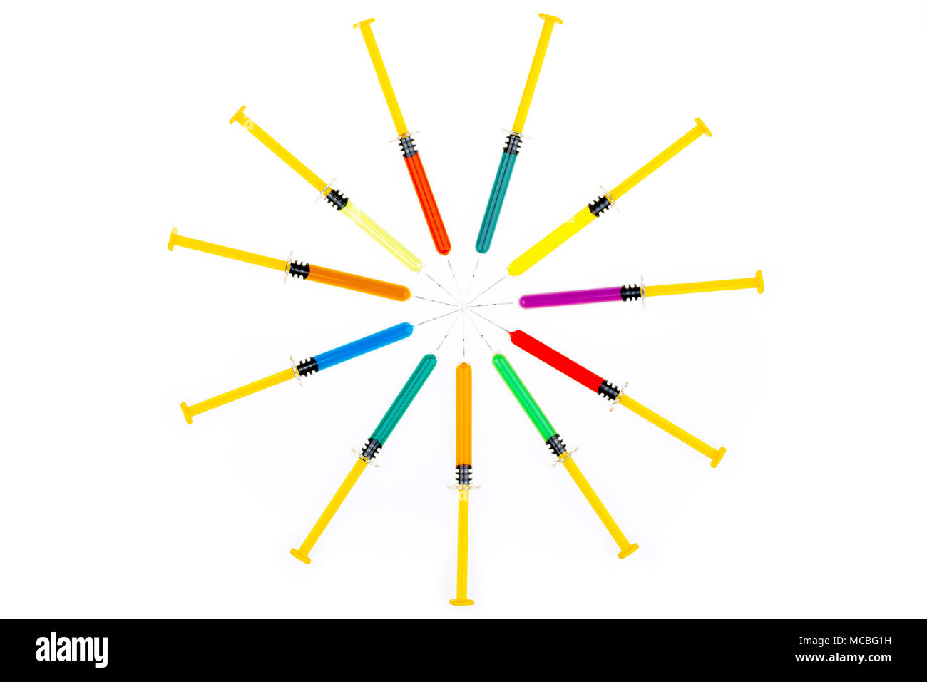 Multiple syringes with needles, filled with various colours of medicine ...