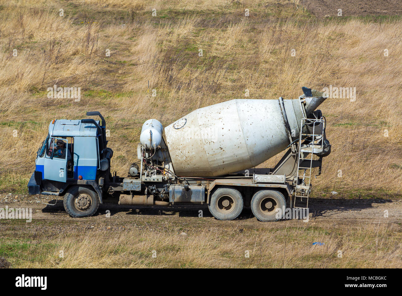 Moving concrete mixer truck on dirty dusty empty field road. Building ...