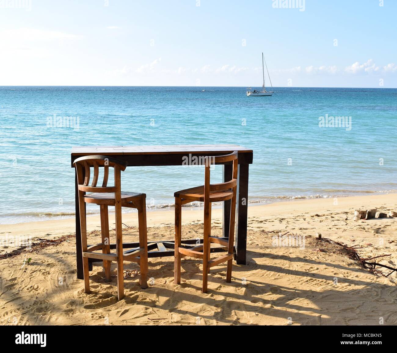 Romantic seascape with wooden table and chairs on sandy beach and a ...