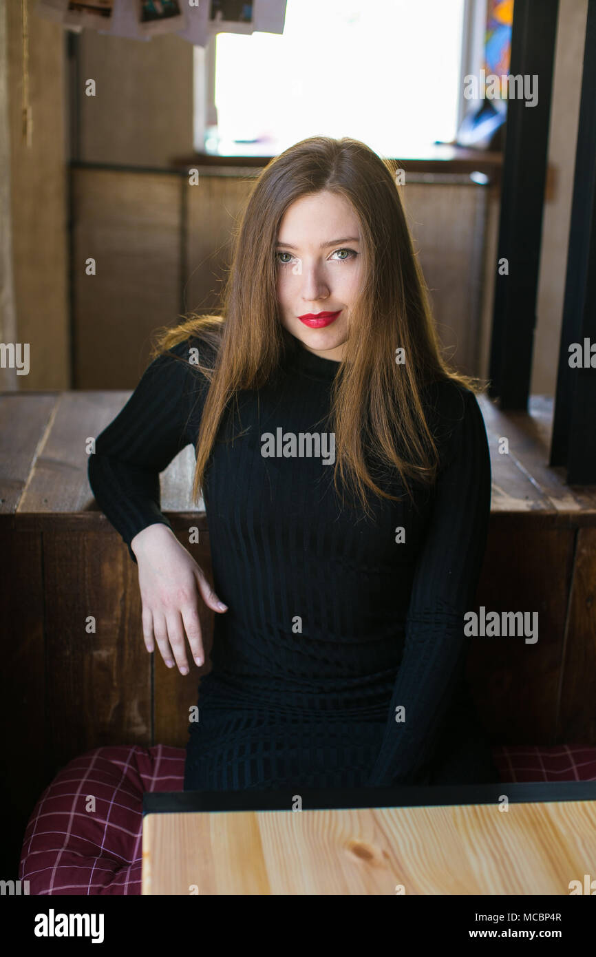 Girl sitting near table in cafe Stock Photo - Alamy