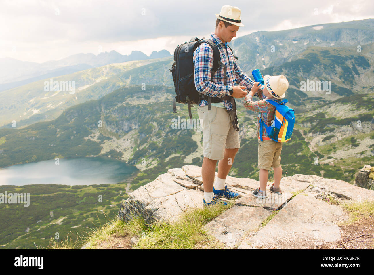 Father and son hiking in Rila mountains, Bulgaria. dad giving water to ...