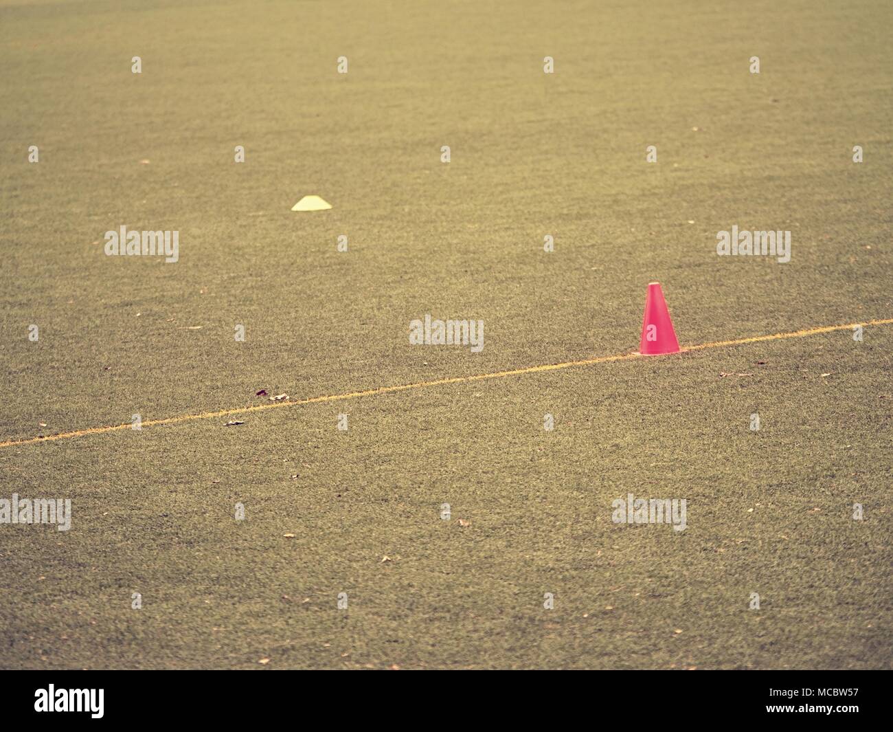 Bright red plastic cone on painted white line of soccer field. Football ...
