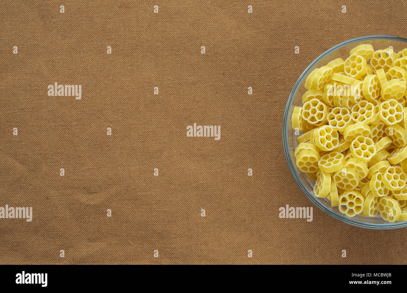 Macaroni ruote Pasta in a glass cup on a brown suburban background ...