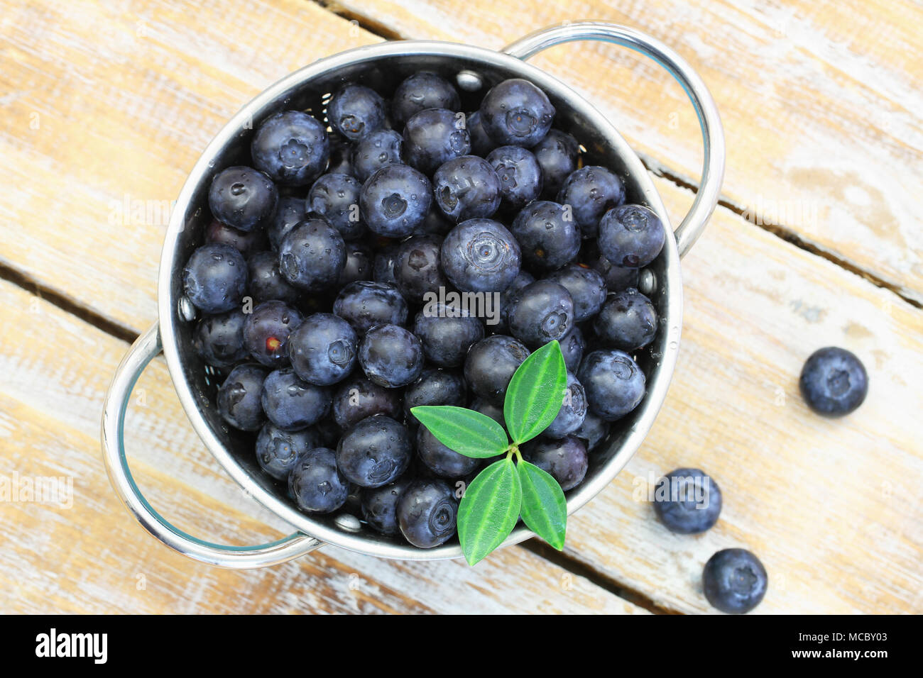Blueberries in metal colander on rustic wooden surface Stock Photo - Alamy
