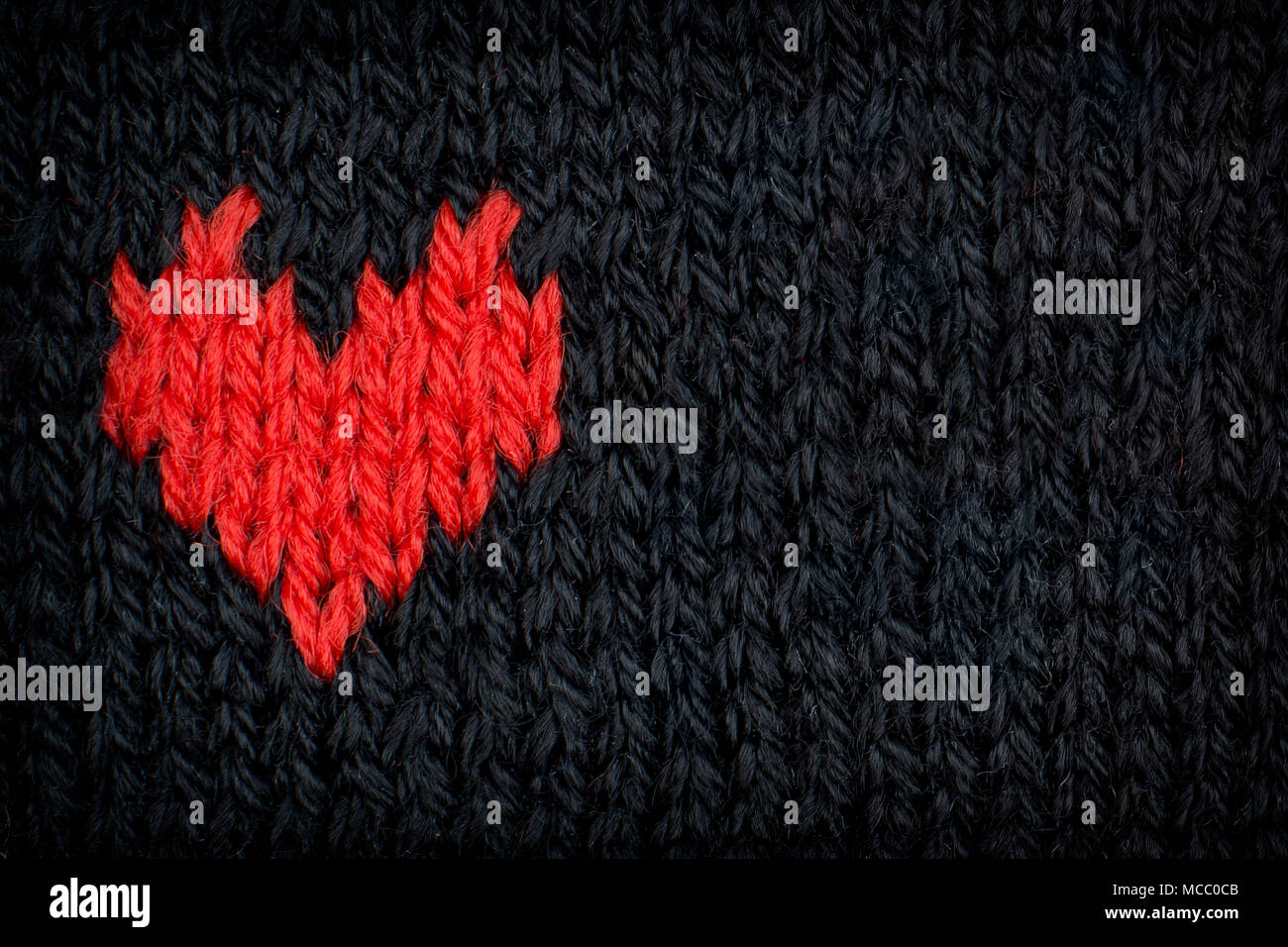 Knitted red heart made of yarn on a black background Stock Photo - Alamy