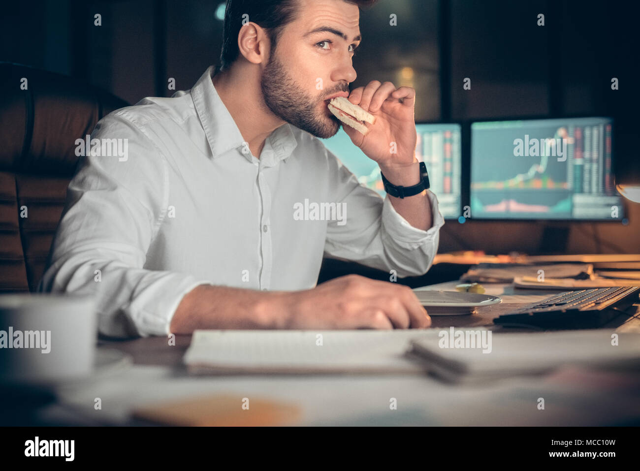 Busy businessman having late lunch eating sandwich in office working at ...