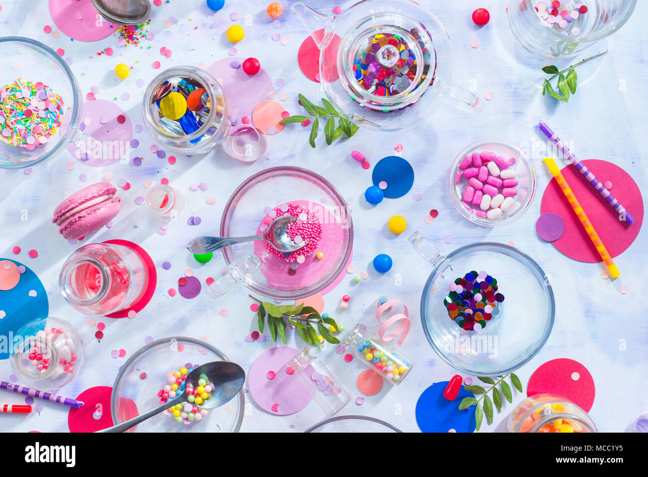 Sprinkles, confetti, candies, macaroons and birthday candles on a white ...