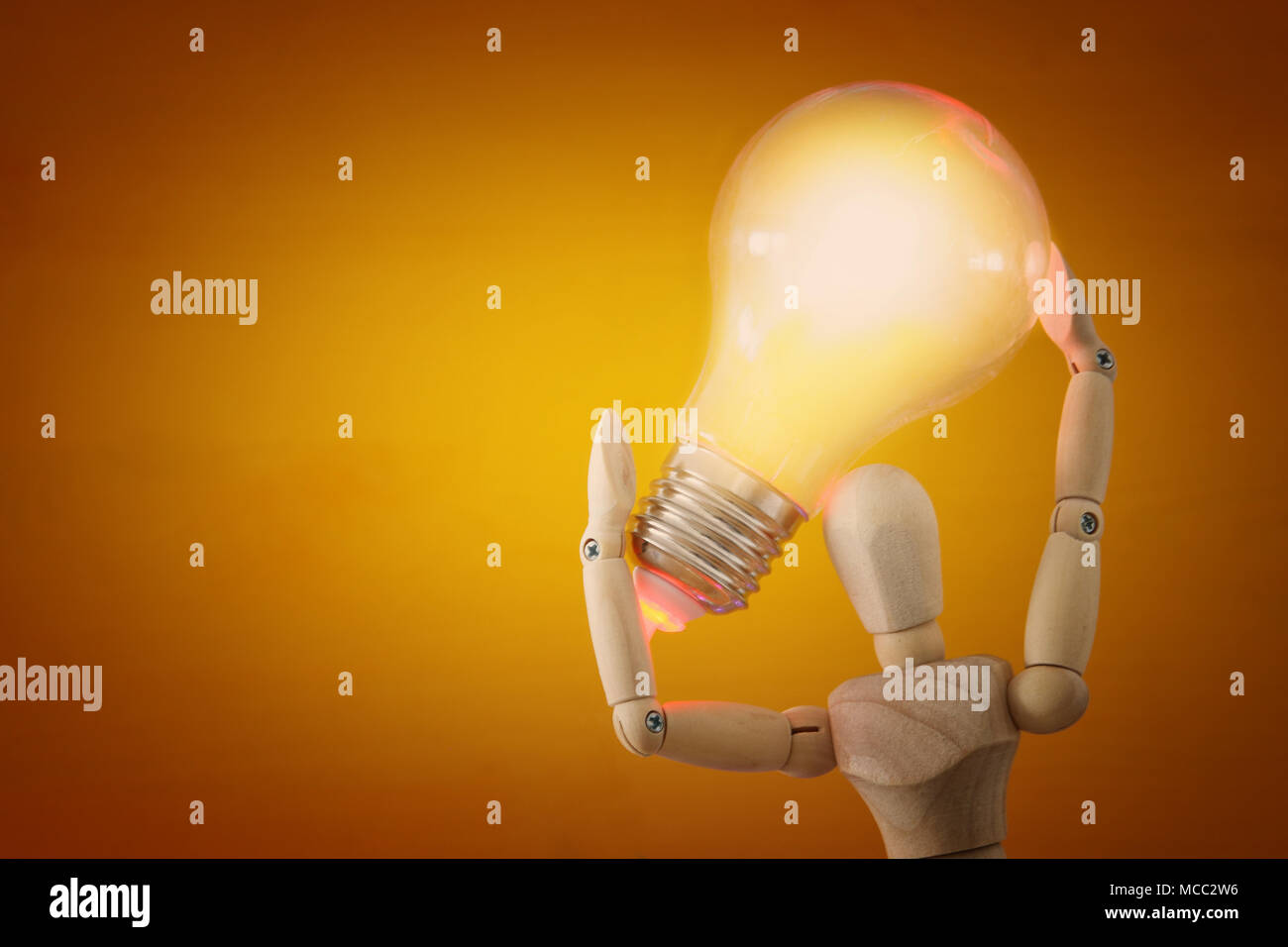 Wooden dummy holding shiny light bulb. New idea concept or choosing the ...