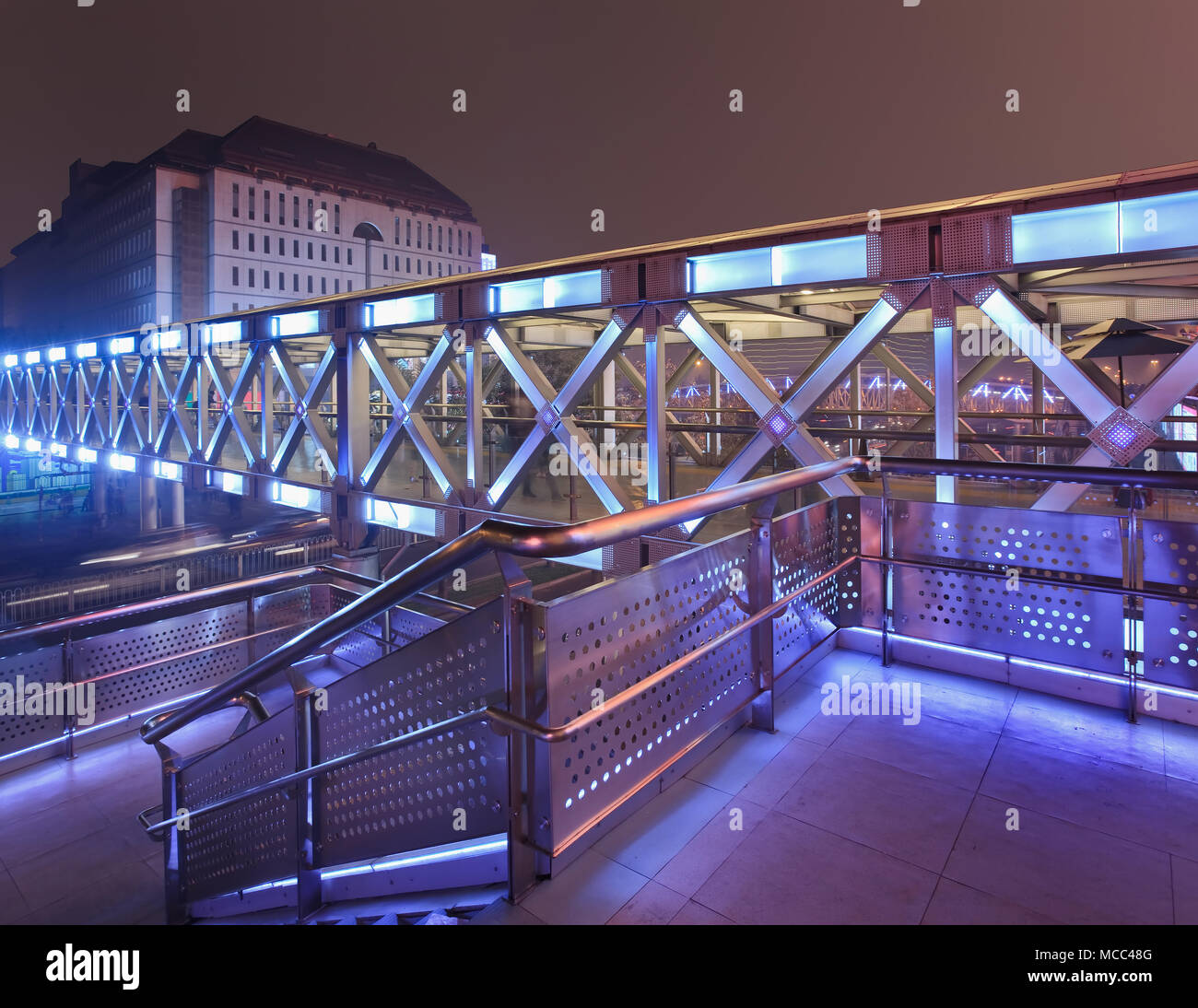 Night scene with illuminated pedestrian fly-over in commercial area ...