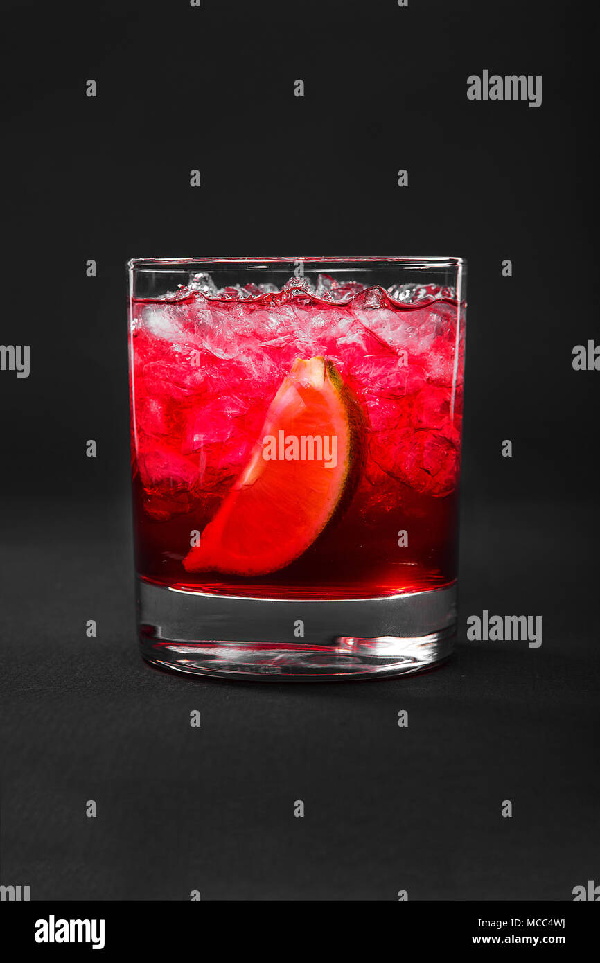 A single-colored, pink, red, transparent cocktail in a low glass with ...