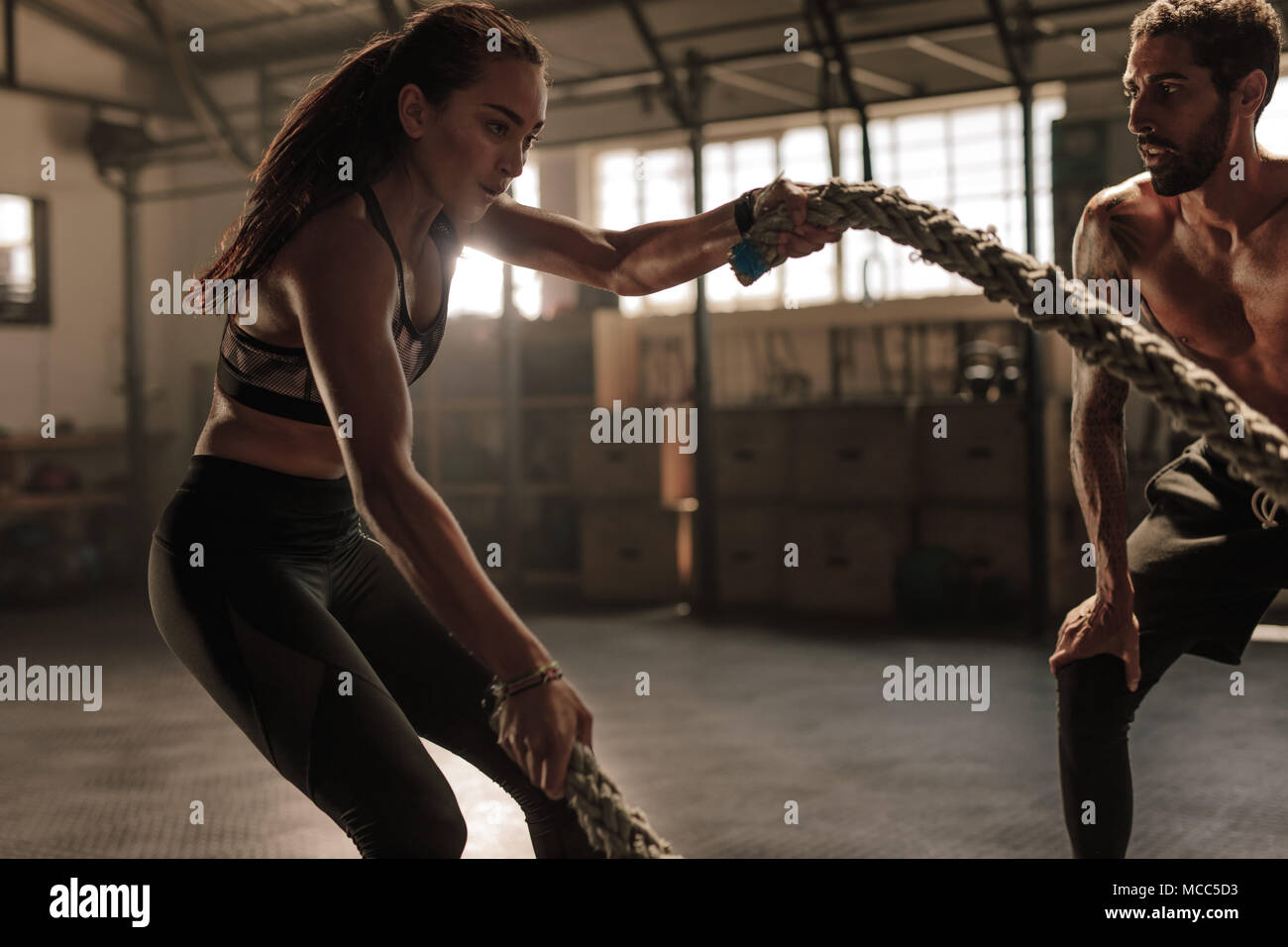 Strong woman workout with battle ropes at the gym with personal trainer ...