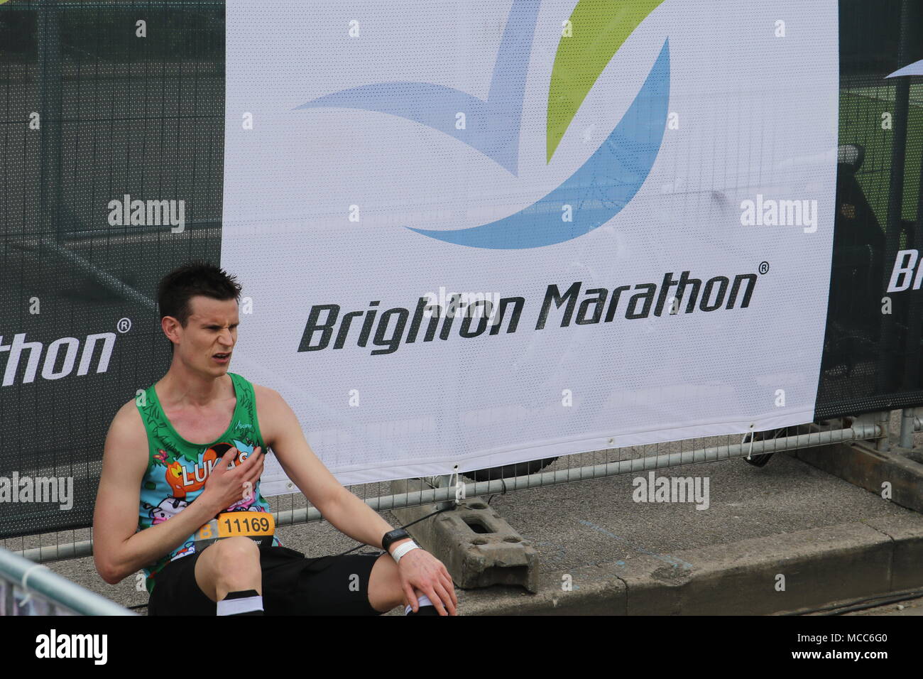 a tired male runner getting support to regain breath at the end of a ...