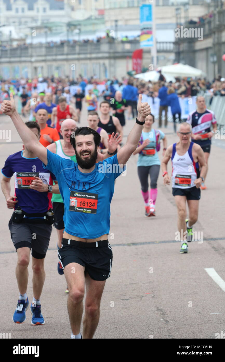 a runner smiling and raising his arms in celebration at the finish line ...