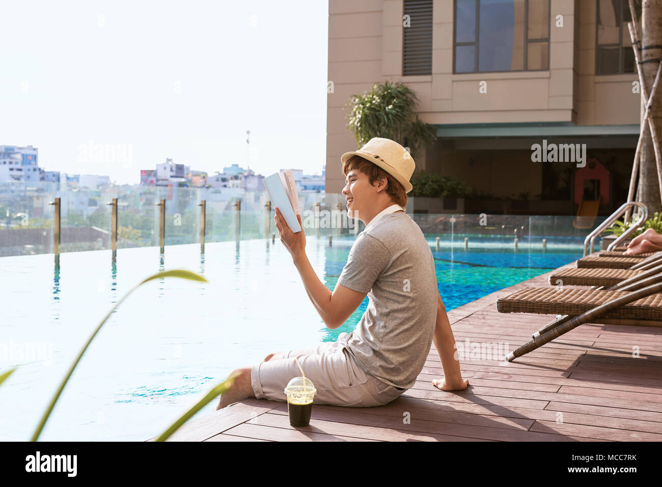 Young asian man reading book by the pool on a sunny summer day Stock ...
