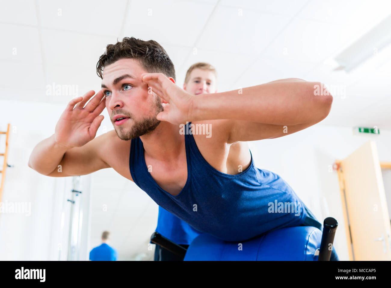 Man at gym on workout bench getting assistance by personal trainer ...