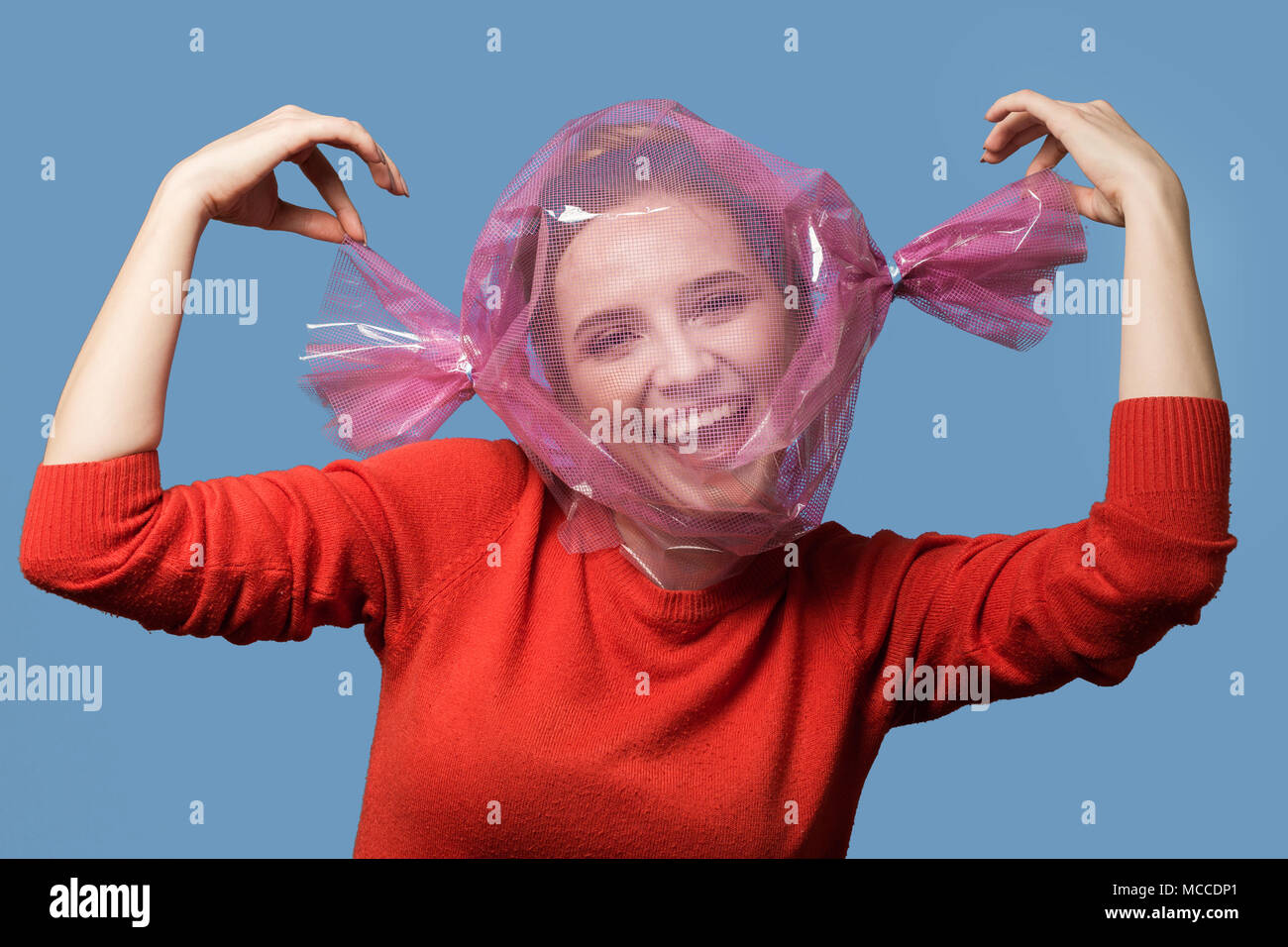 fun girl with head inside candy wrapper on blue background Stock Photo ...