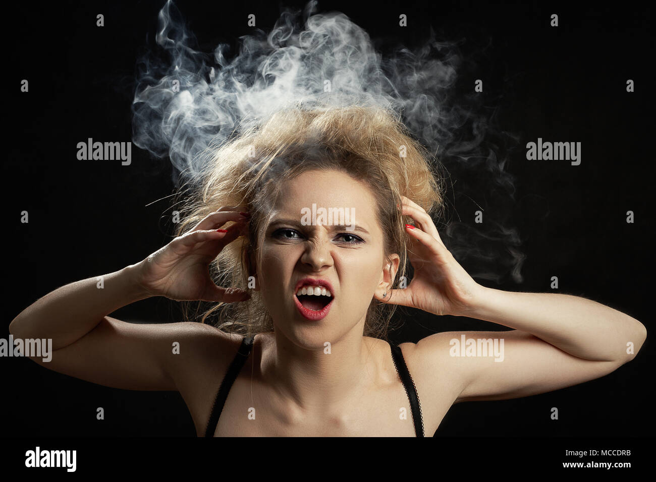 stressed woman with cloud of smoke on her head on black background ...