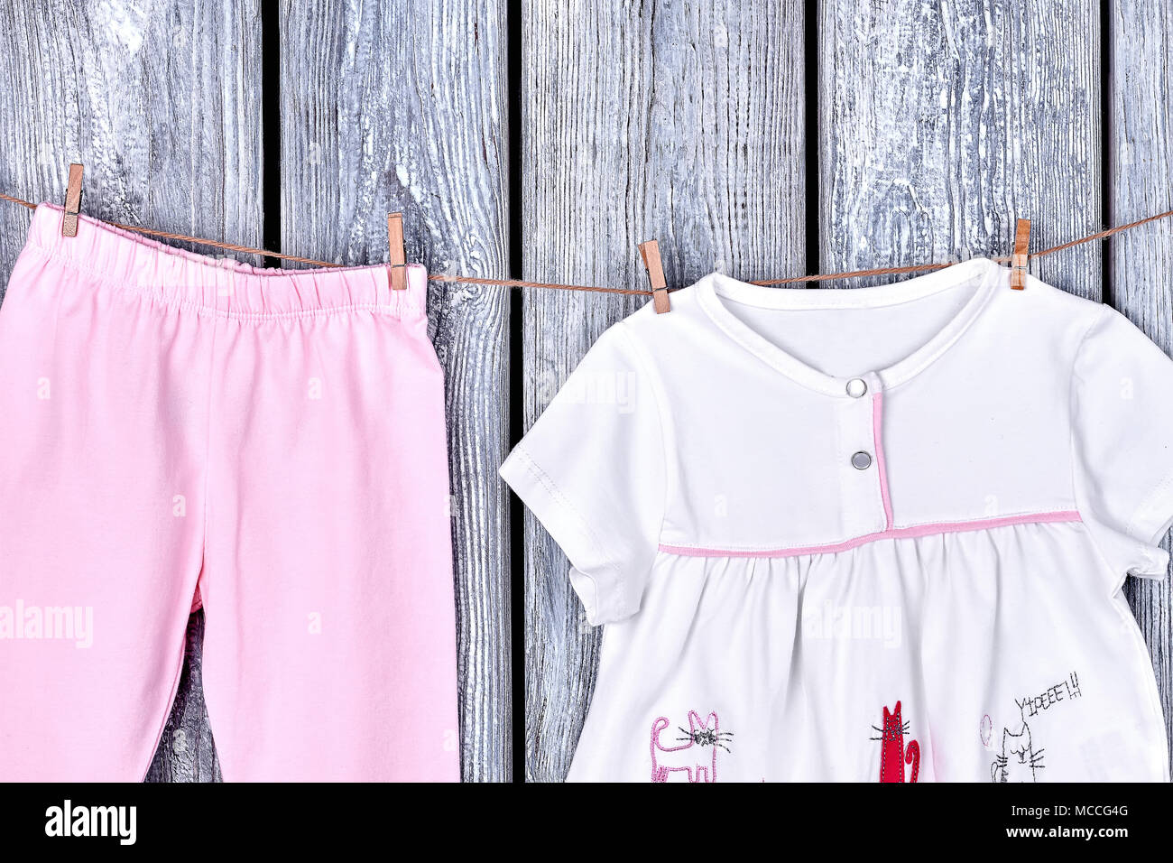 Infant girl clothing on rope. Toddler girl top and pants hanging on ...