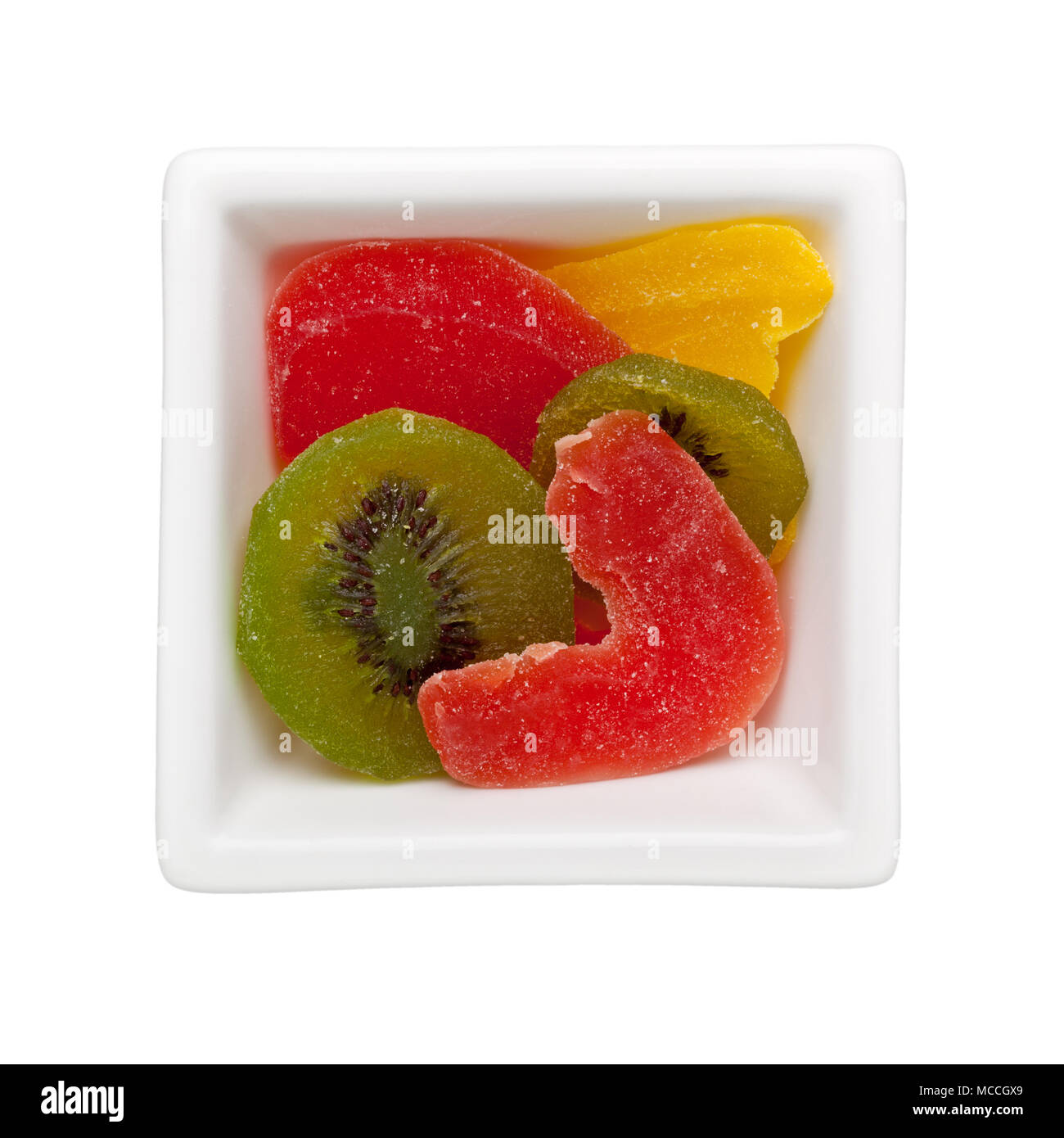 Pieces of candied fruits in a square bowl isolated on white background ...