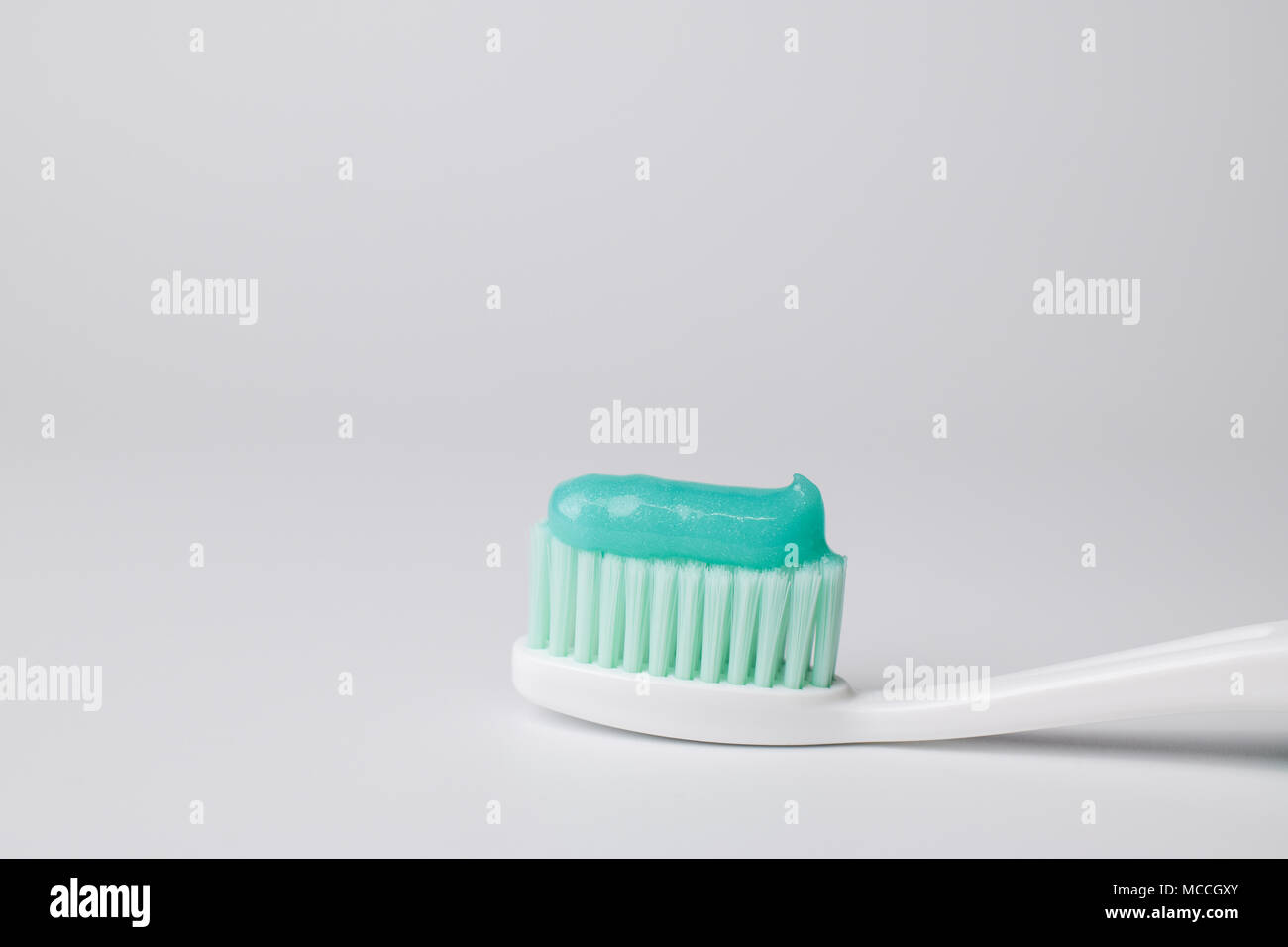 Green toothpaste on a toothbrush on white background - closeup Stock ...