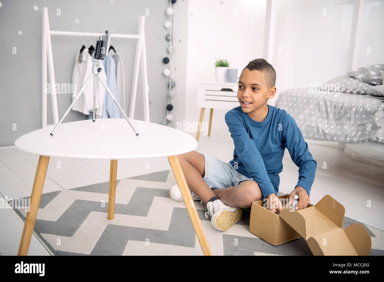 Positive boy blogger unboxing parcel Stock Photo - Alamy