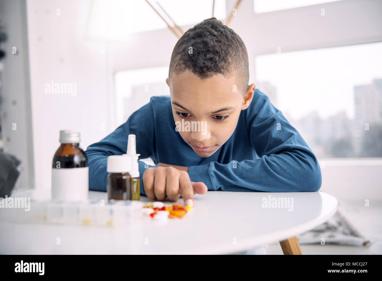 Attentive focused boy counting pills Stock Photo - Alamy