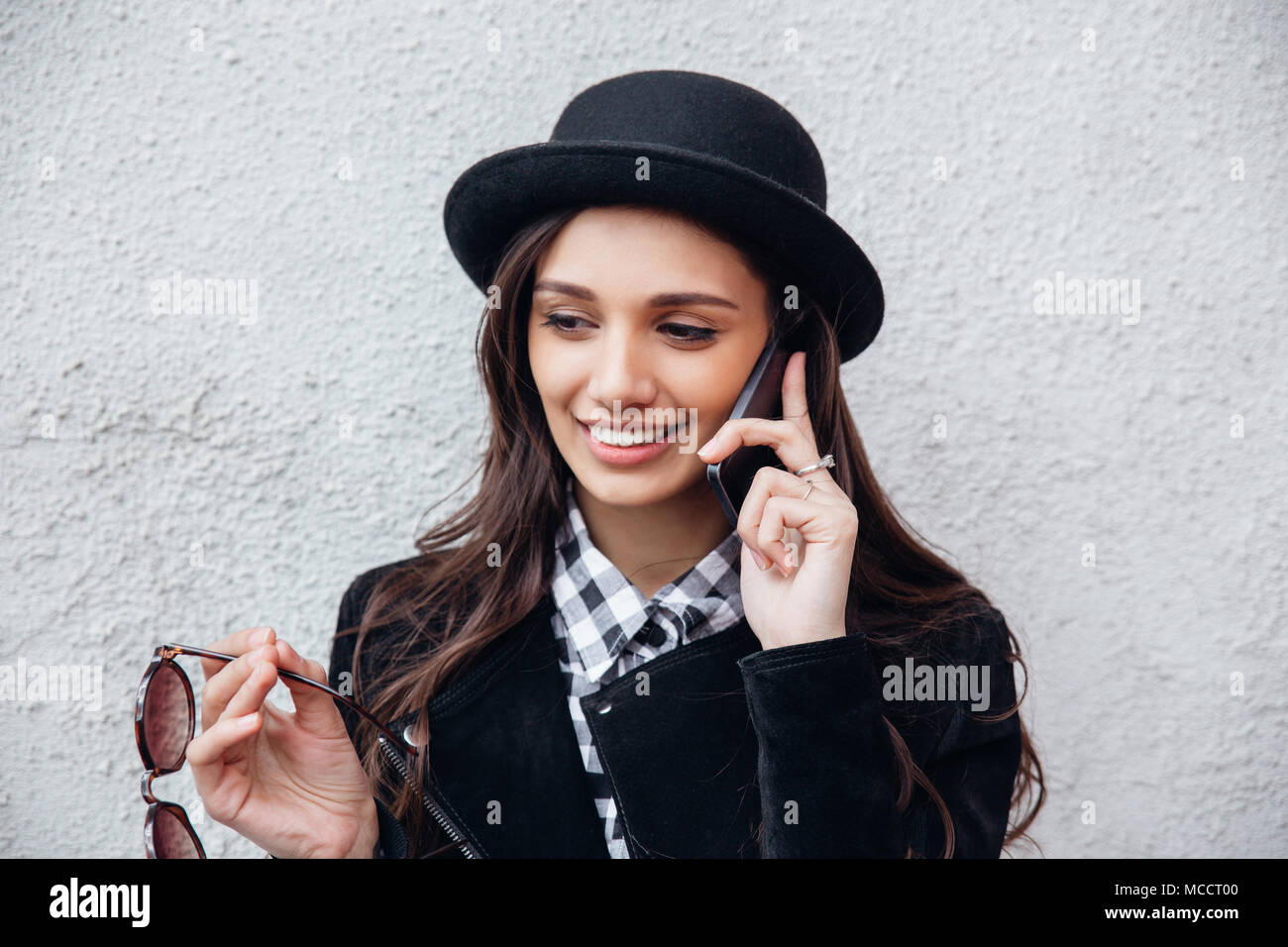 Smiling urban girl uses smart phone with smile on her face.Portrait of ...