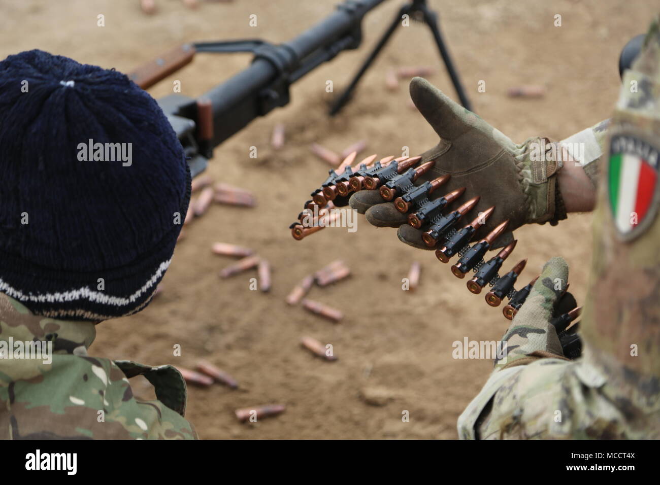 An Italian coalition member hands an Iraqi soldier a belt of ammunition ...