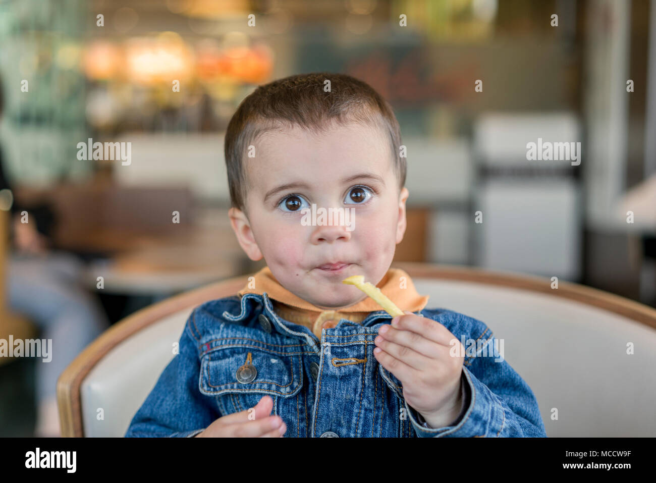 A happy baby boy eats French fries. fast food. European Stock Photo - Alamy