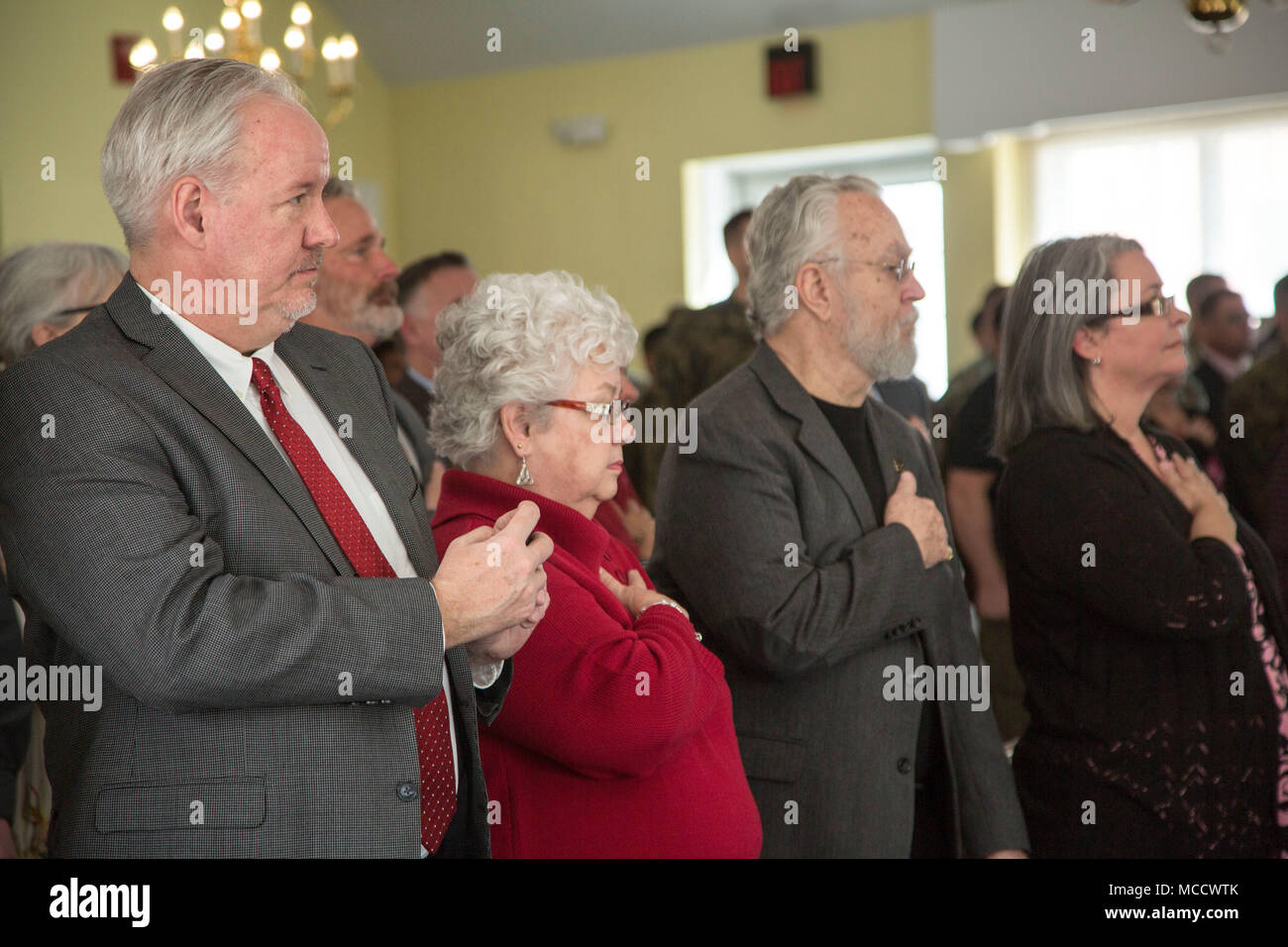 Family members stand for the national anthem during a retirement ...