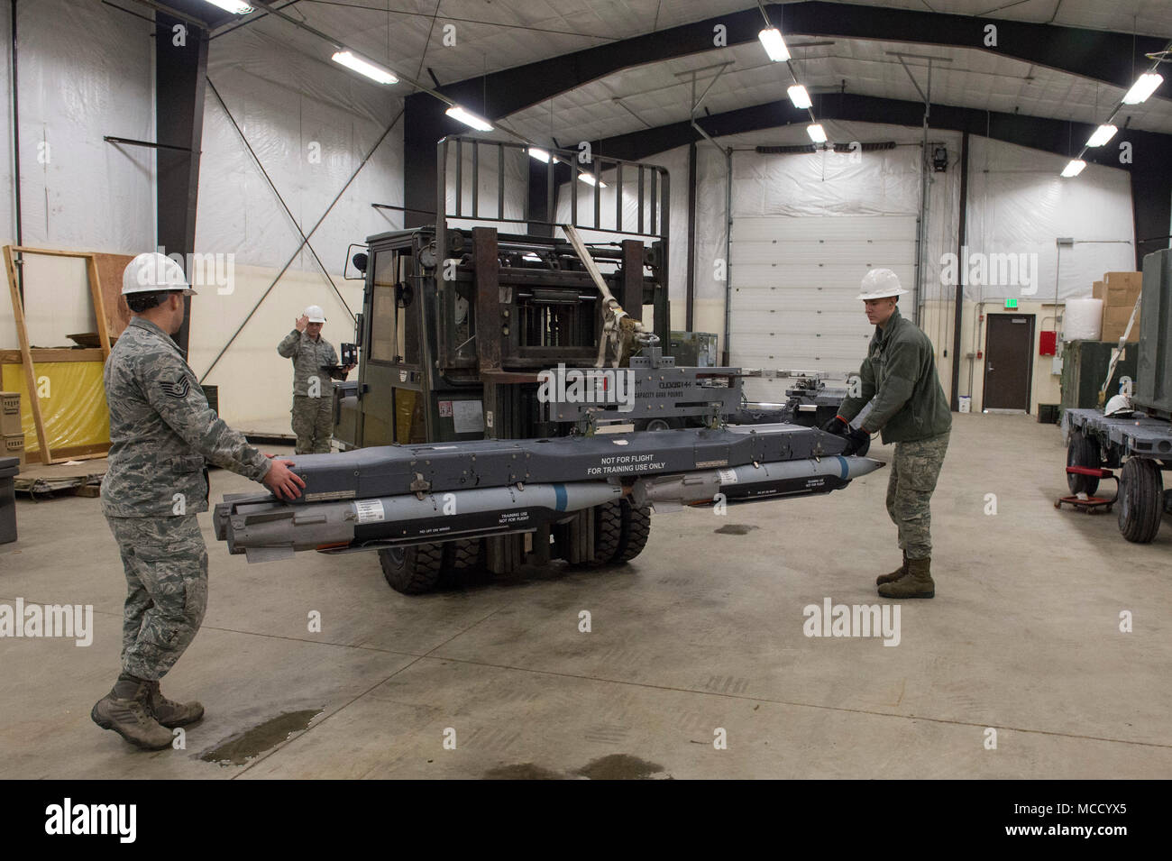 Airmen with the 3rd Munitions Squadron transport a rack of inert small ...