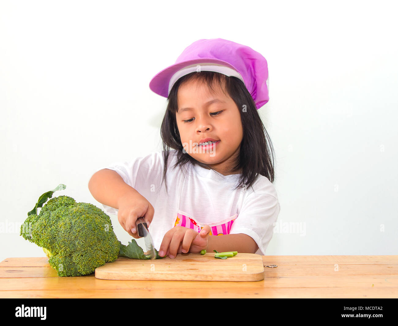 Little girl is cutting vegetable for salad using kitchen knife Stock ...