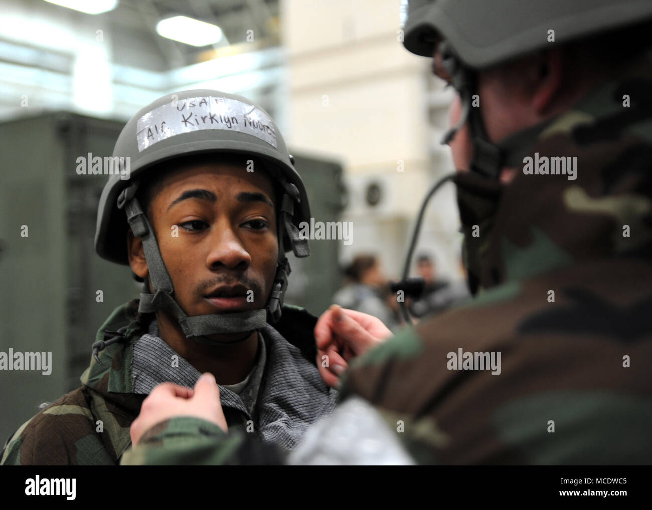 An Airman assists a wingman with his helmet during an exercise Feb. 21 ...