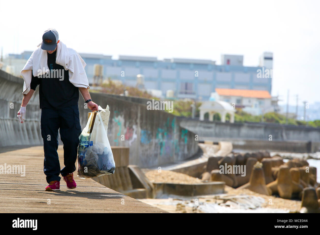 SUNABE, SEAWALL, OKINAWA, Japan- Sgt. Mark Winkles looks for trash during a beach cleanup Feb ...