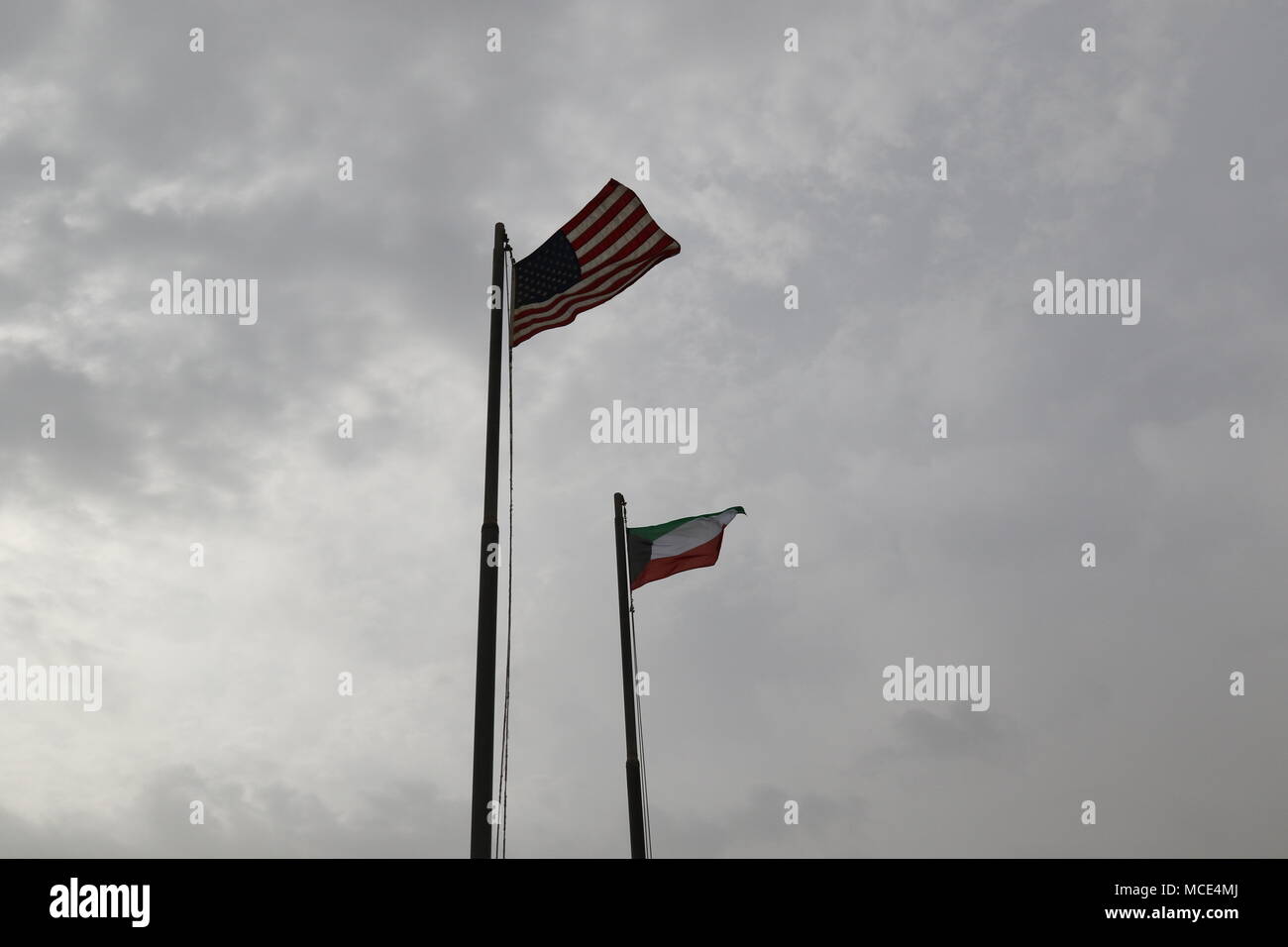 A new Kuwaiti flag flies by the American flag during a ceremony on Camp ...
