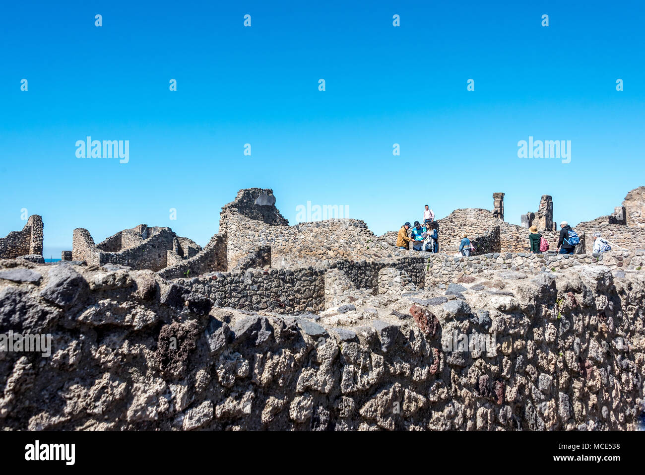 Tourists explore a section of Pompeii city ruins facing the ...